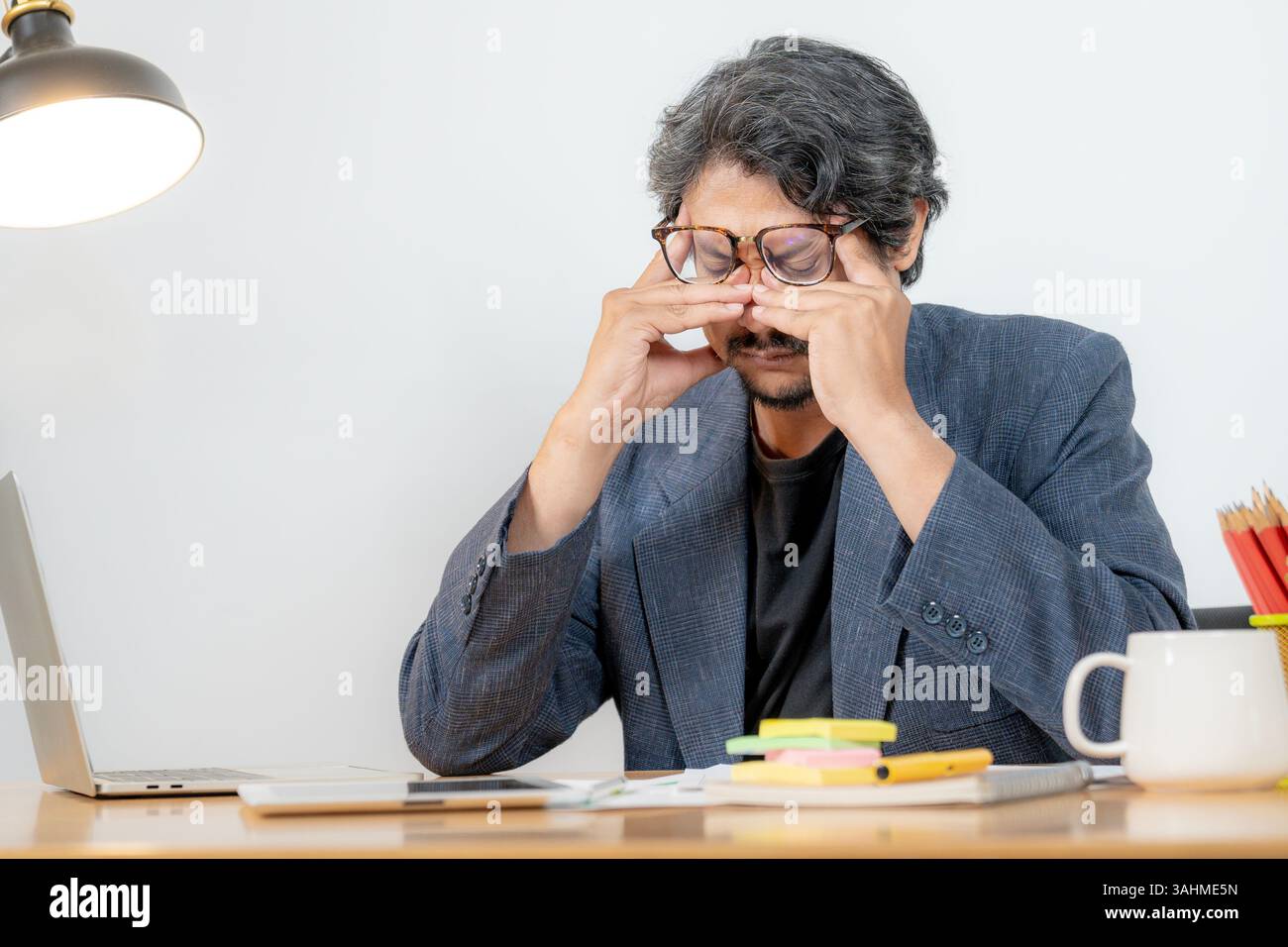 A young businessman staring at his computer screen for hours, rubbing ...