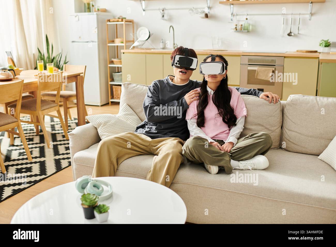A young Asian couple shares a fun moment in their home, immersed in virtual reality Stock Photo ...