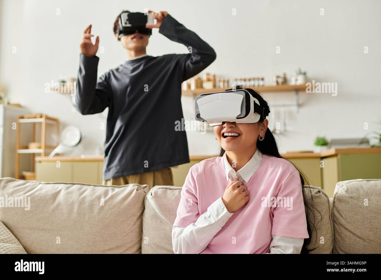 A young asian couple experiences virtual reality in their cozy home ...