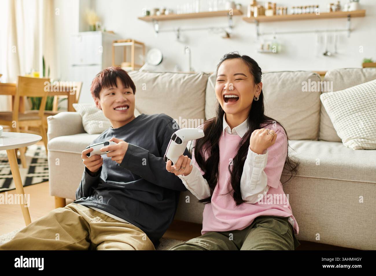 A young asian couple shares laughter and fun while gaming on a ...