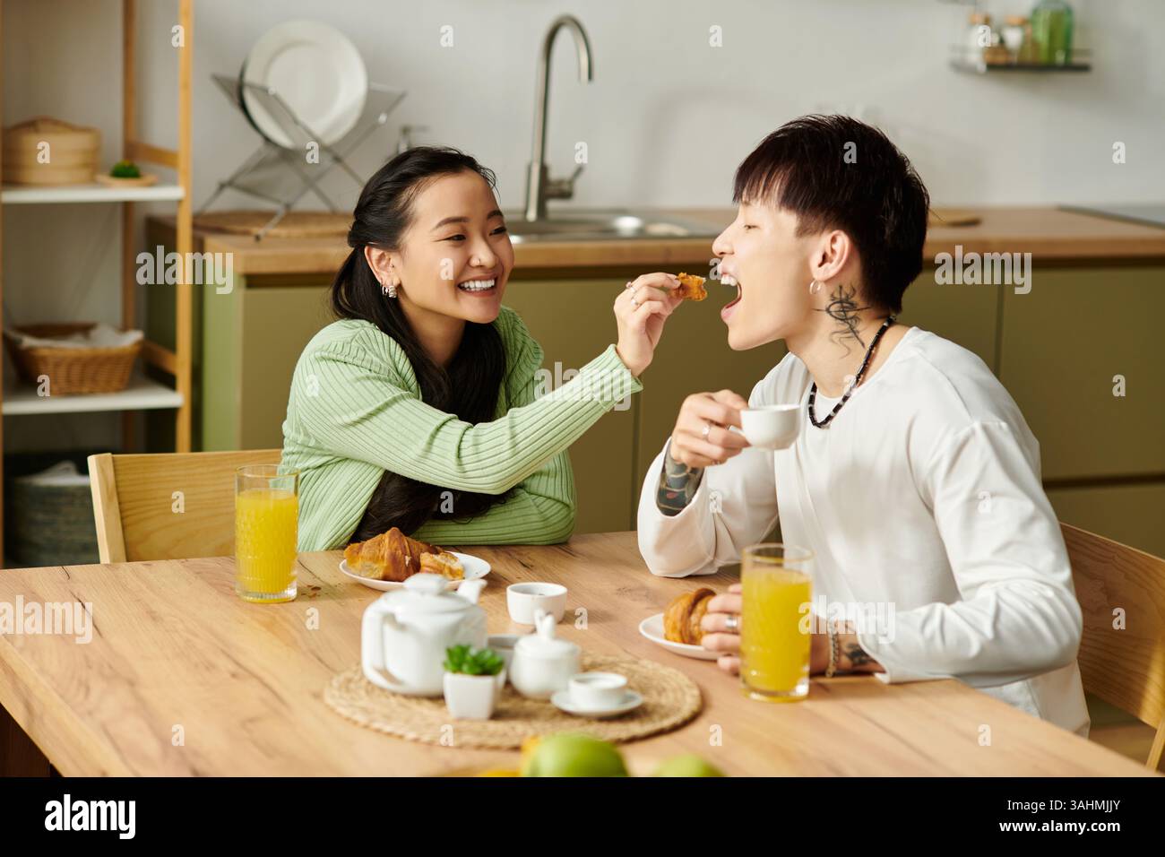 A cheerful young couple shares homemade breakfast and laughter in their ...