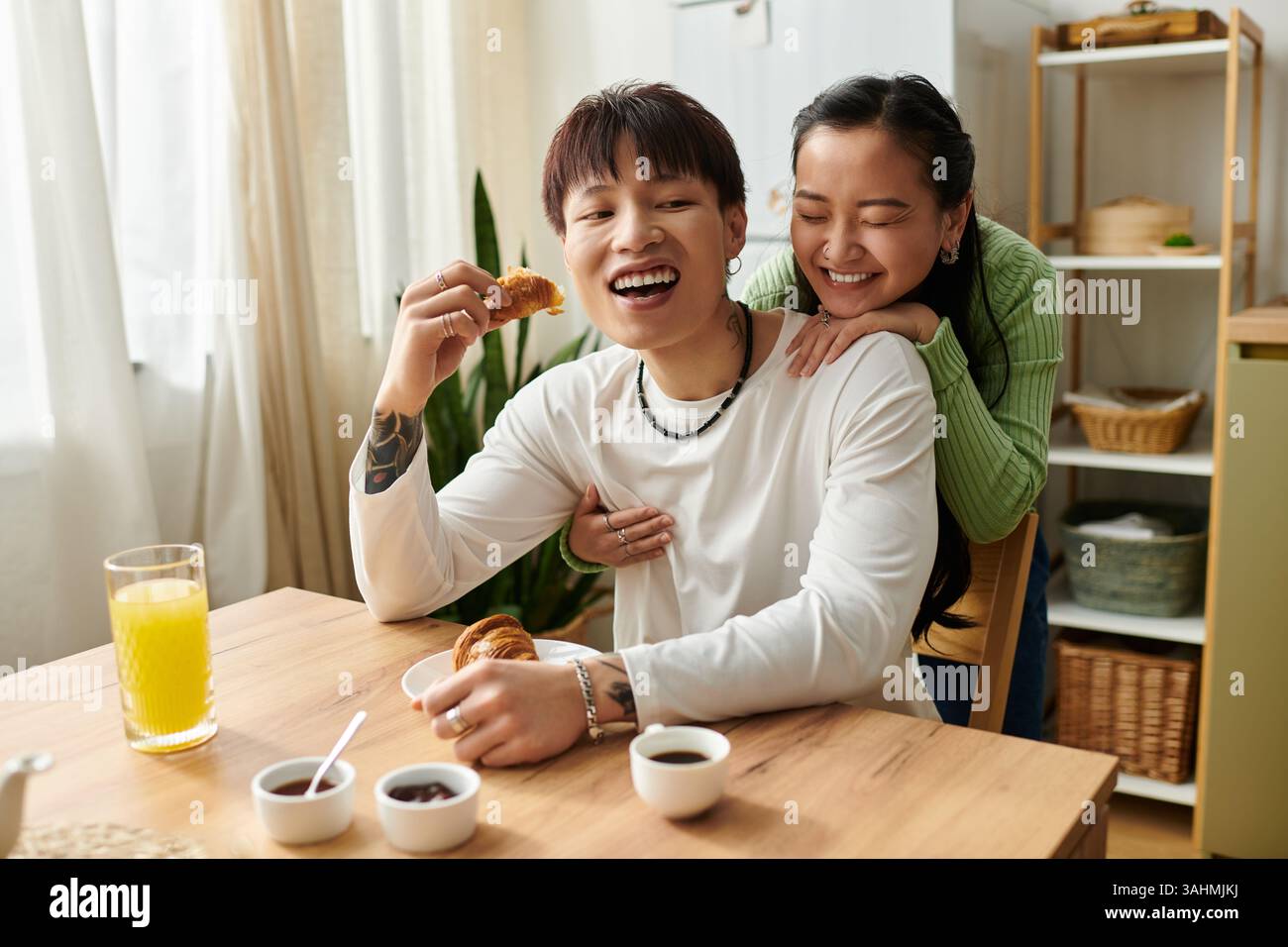 A young asian couple enjoys a cheerful breakfast together at home ...