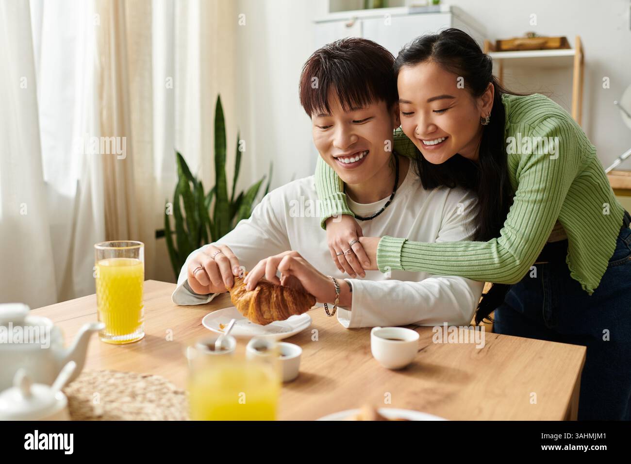 A young asian couple enjoys a cozy breakfast, sharing laughter and ...
