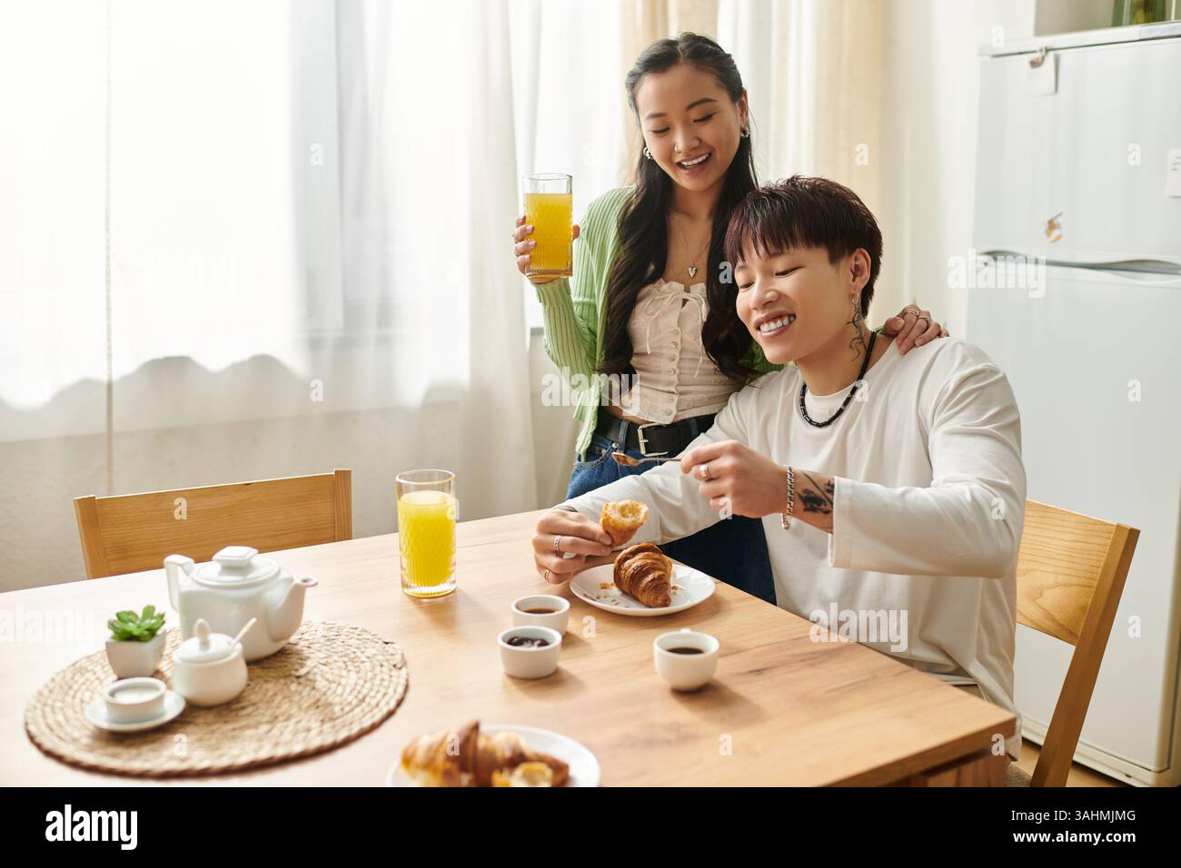 A young Asian couple enjoys a cozy breakfast together, sharing laughter ...