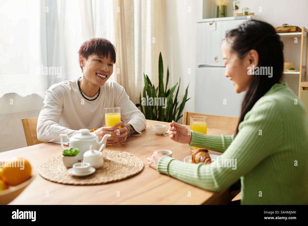 A young couple enjoys breakfast together at home, smiling and sharing ...