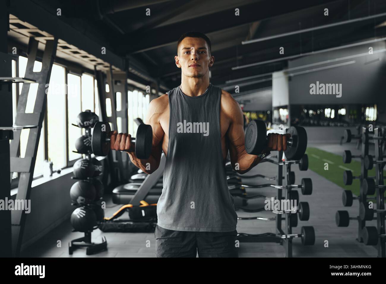Strong bodybuilder male in sportswear training biceps muscles with ...