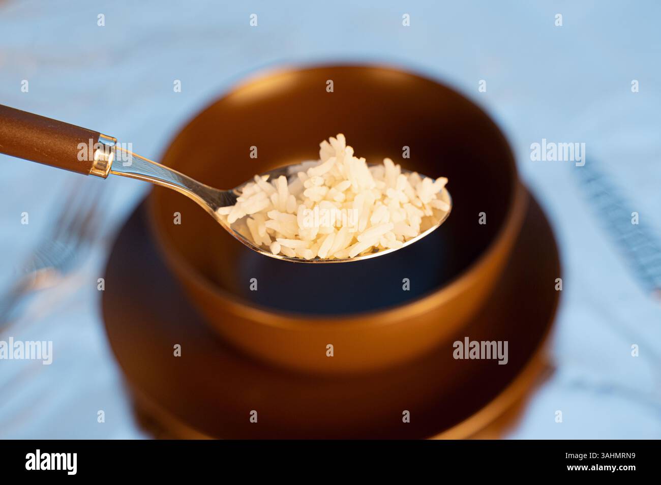 A spoonful of delicious rice is being gracefully poured into a neatly ...
