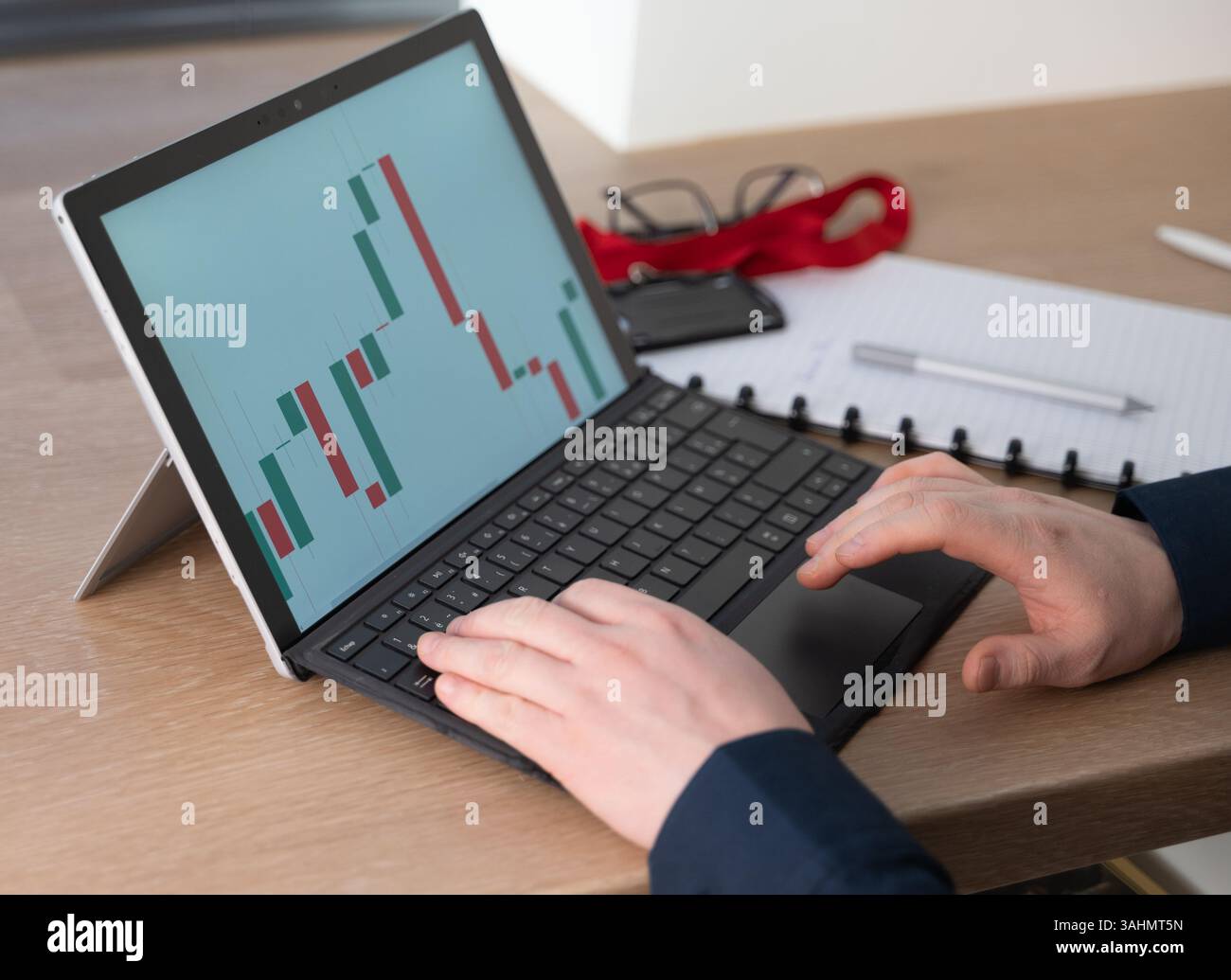 This is a detailed, closeup view of hands actively typing on a laptop that displays various ...
