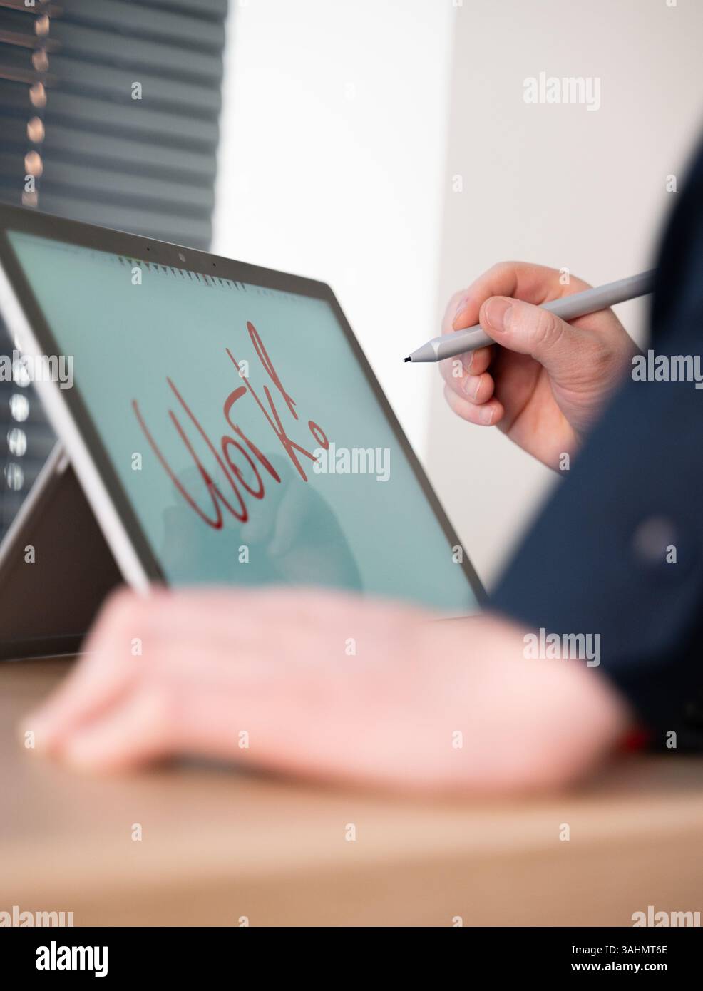 A person is using a sleek digital tablet to creatively write the word ...