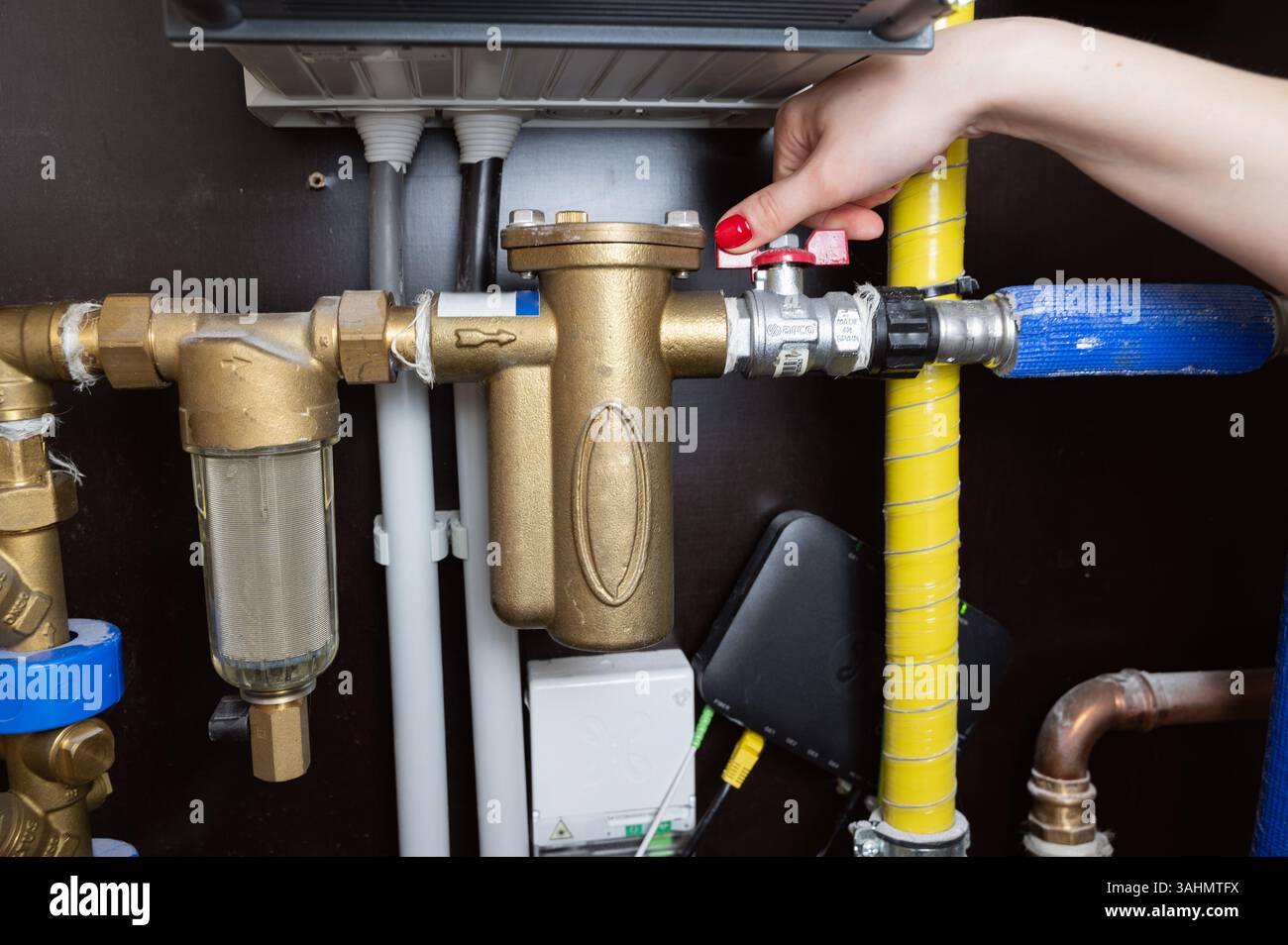A closeup image shows a hand skillfully operating a plumbing valve ...