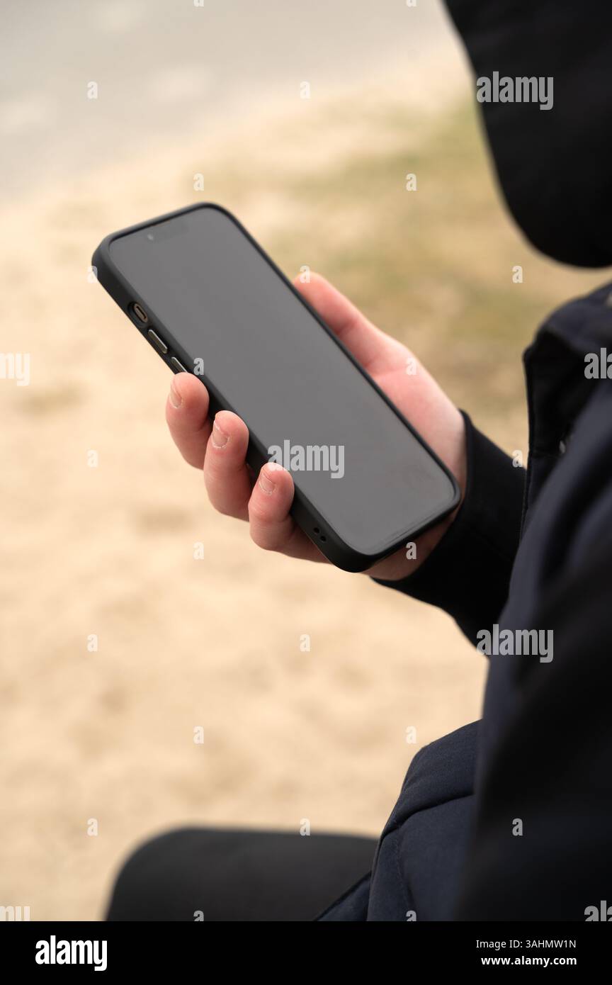 A closeup shot of an individual outdoors holding a smartphone ...