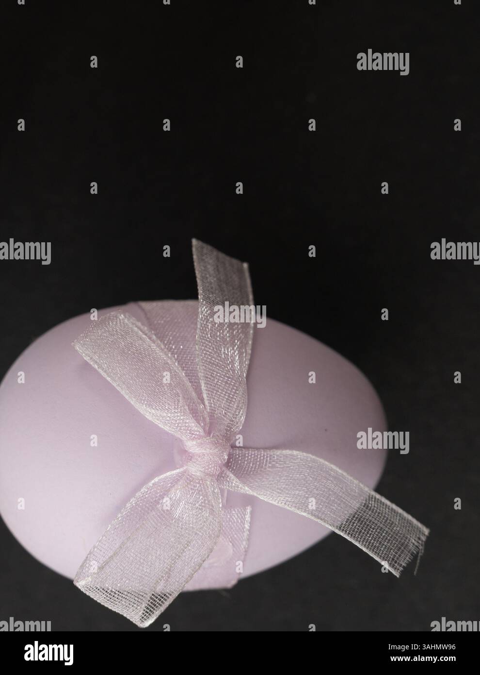 A delightful pink egg adorned with a lovely white bow resting elegantly ...