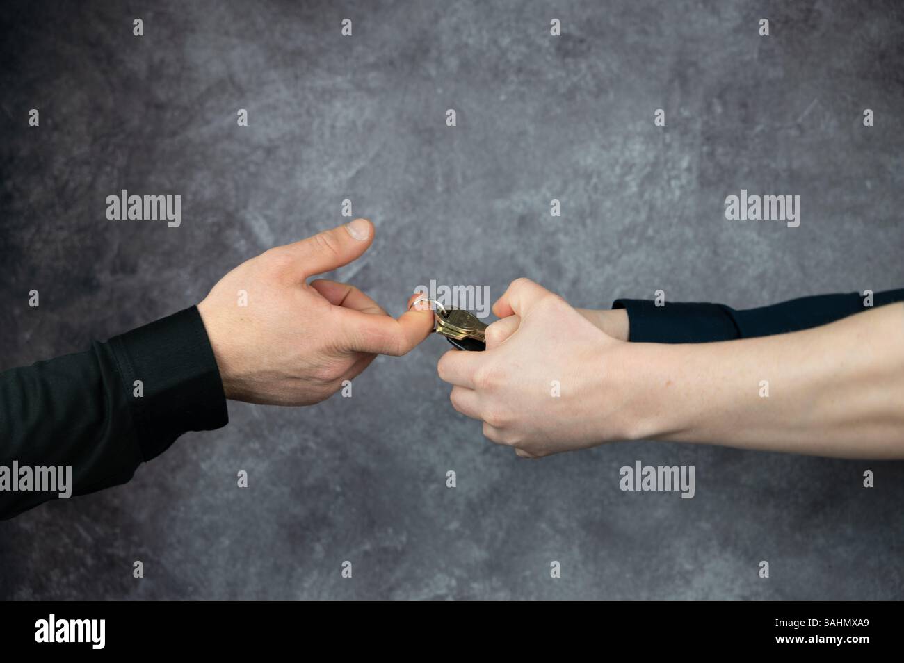 A close-up of one person handing over a set of keys to another ...