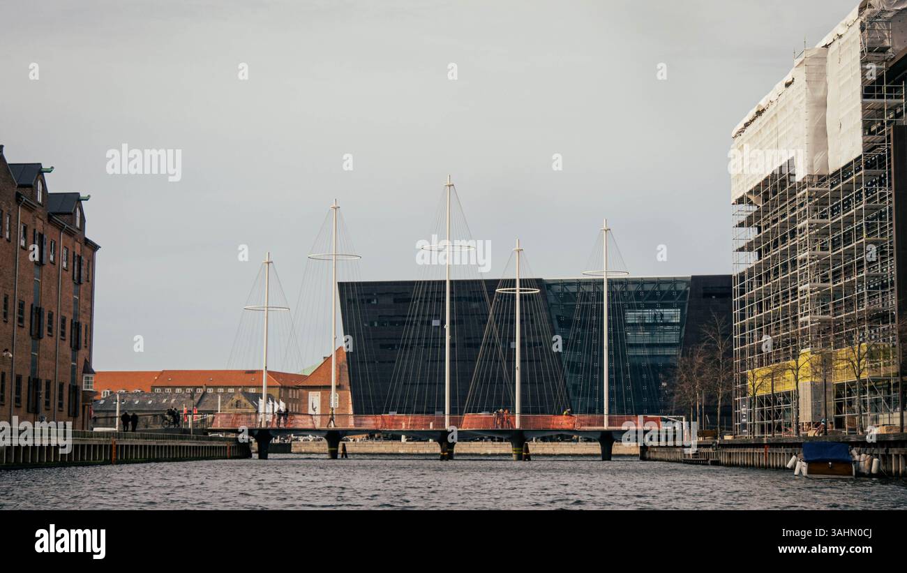 A sleek, modern bridge crossing a waterway in central Copenhagen ...