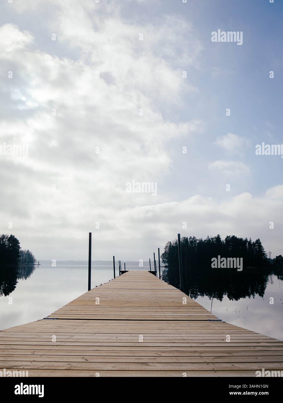 A peaceful scene of a wooden boat dock on a lake in Sweden, surrounded ...