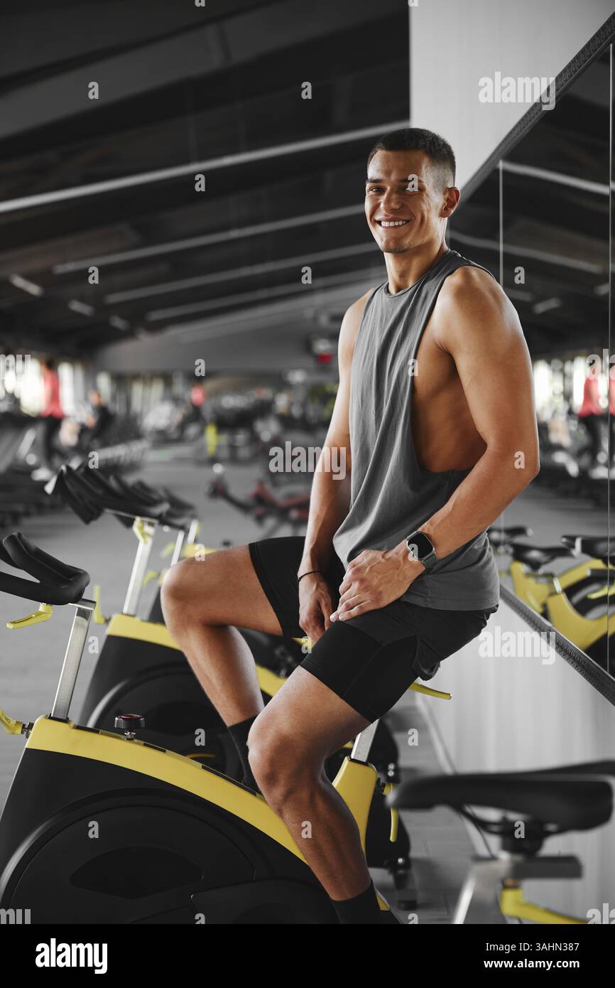 Vertical photo of young man in sportive outfit smiling while sitting on ...