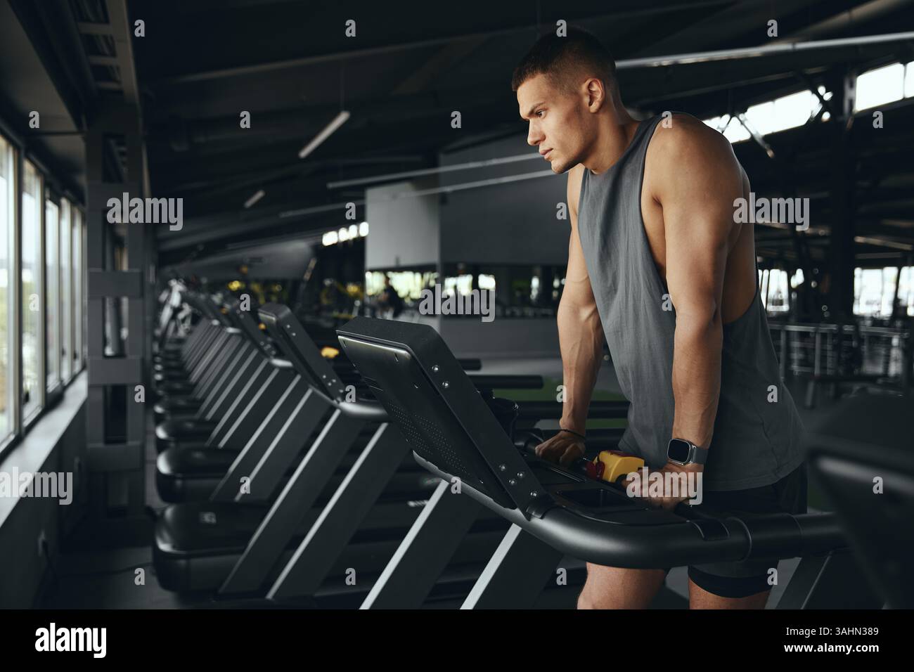 Healthy focused guy resting after running on treadmill at gym for body ...