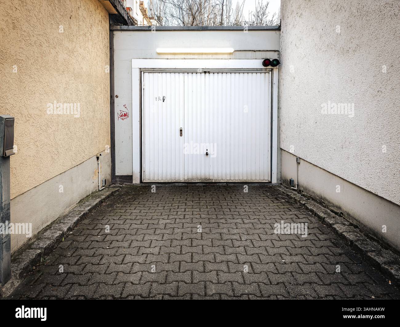 White, ribbed metal garage door in an urban setting, flanked by light ...