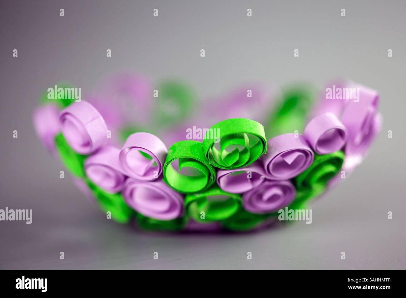 A close-up of a decorative bowl crafted from intricately rolled purple ...