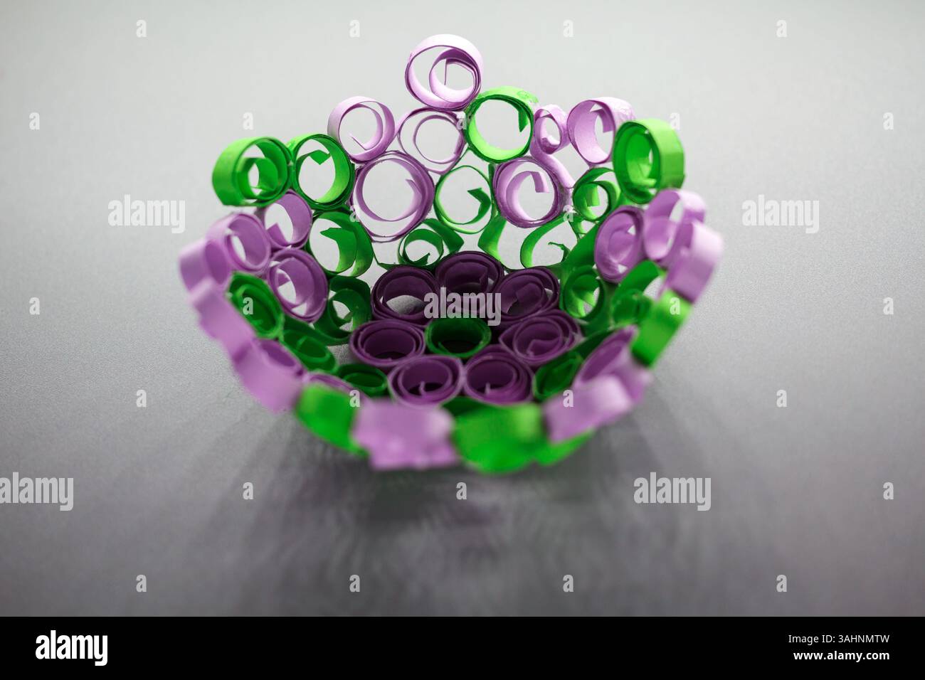 A close-up of a decorative bowl crafted from intricately rolled purple ...