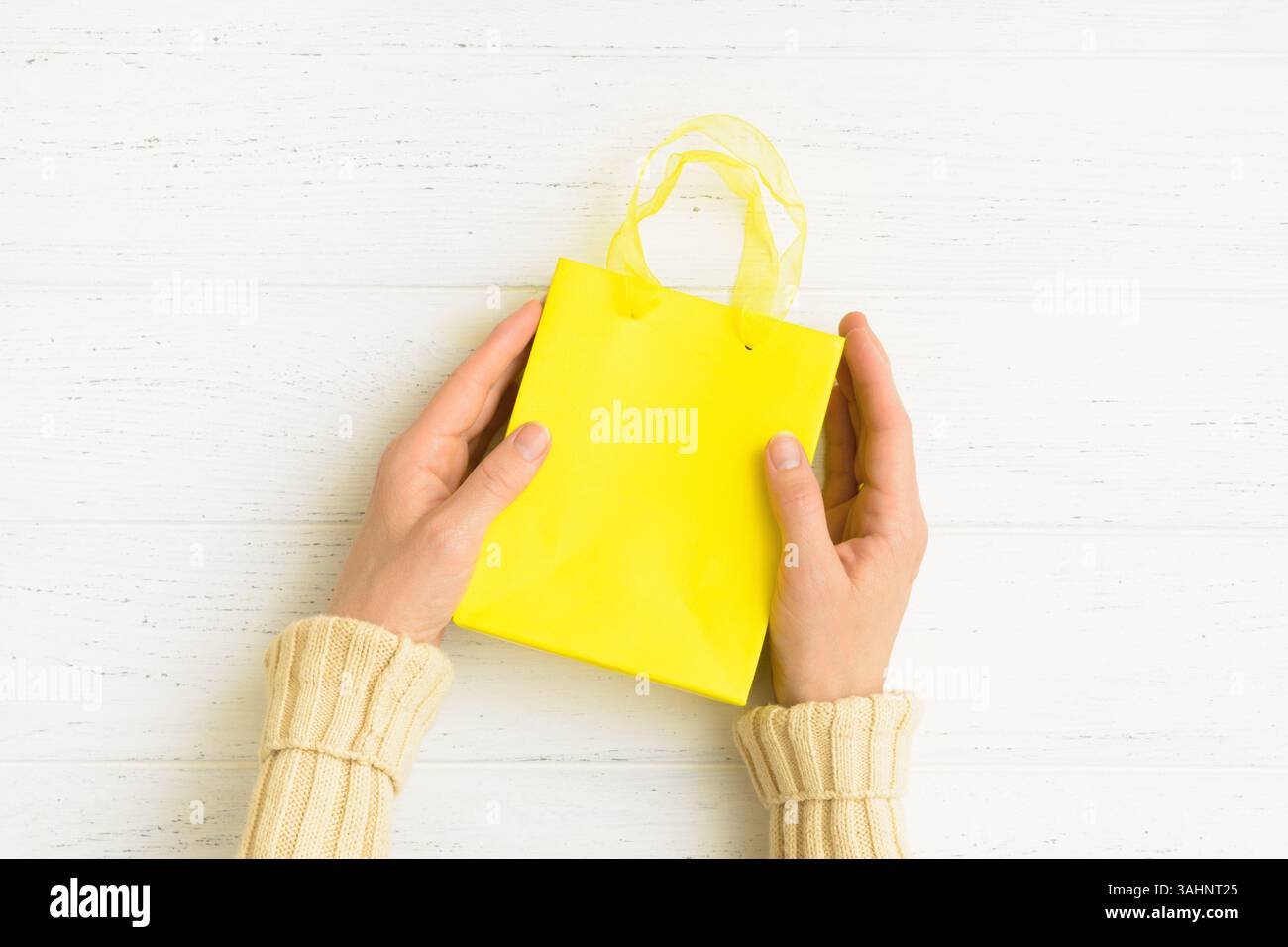 Yellow paper bag in woman's hands over wooden table. Top view Stock ...