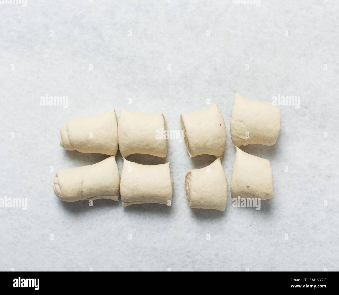 Overhead view of baozi dough being shaped on a white granite countertop ...