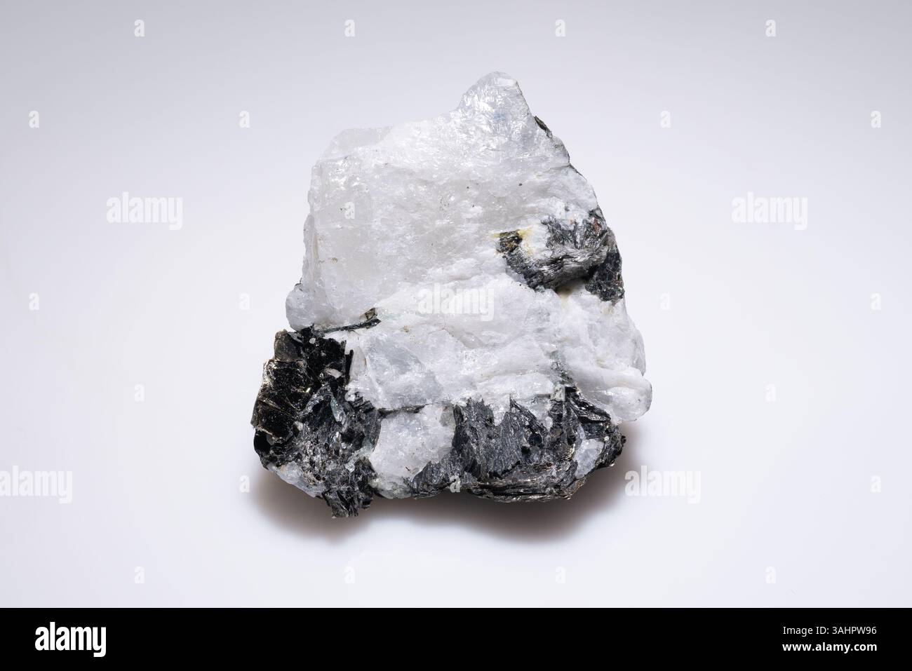 Raw moonstone crystal specimen with dark inclusions against a plain ...