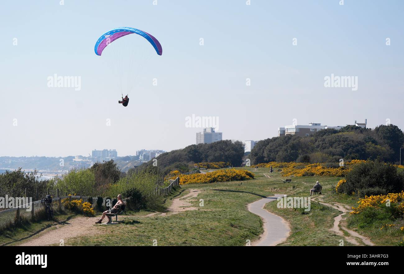 A person paraglides over the cliffs above Boscombe beach in Dorset, in ...
