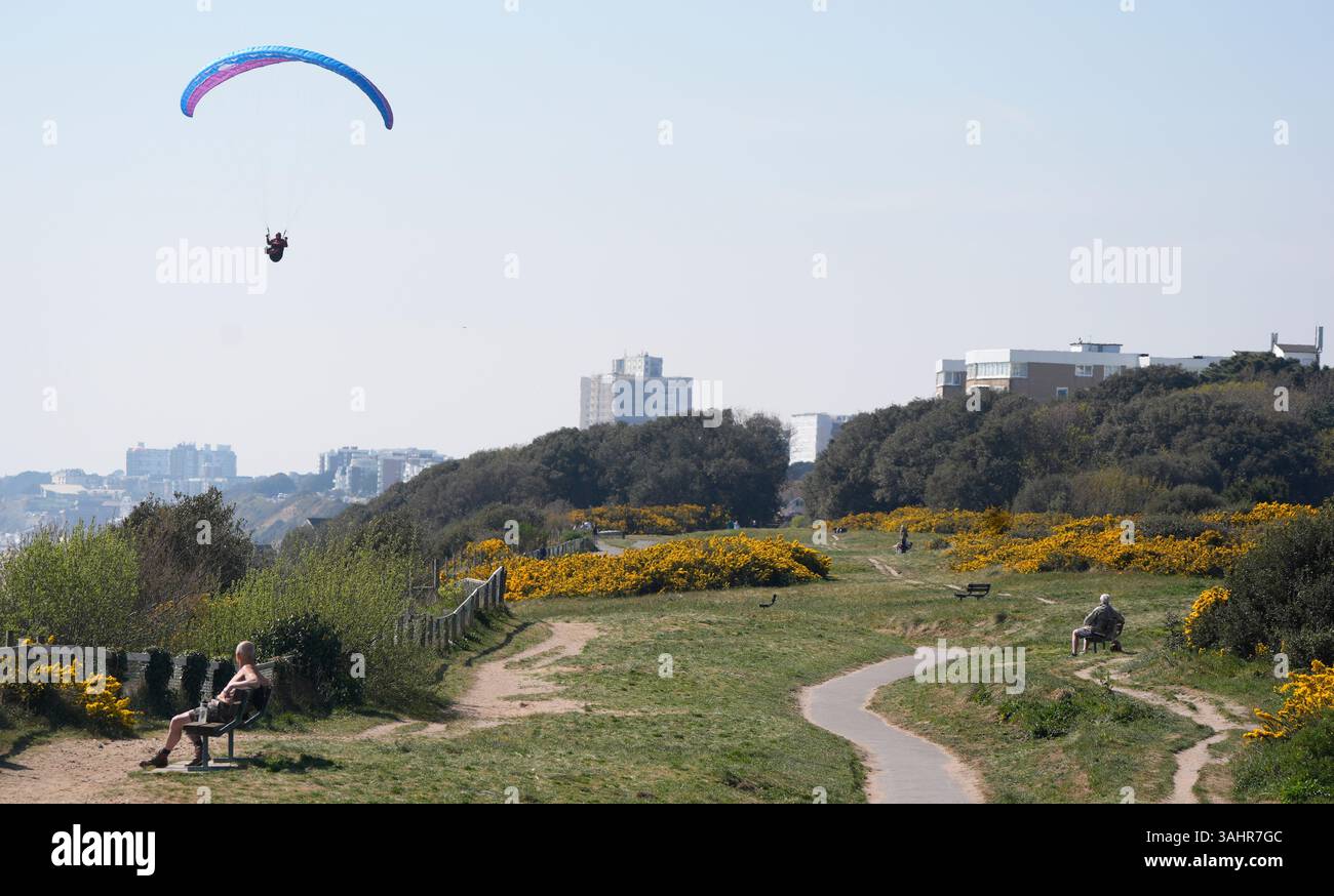 A person paraglides over the cliffs above Boscombe beach in Dorset, in ...