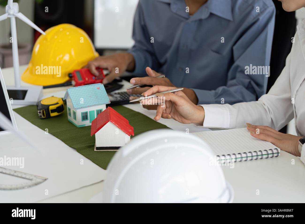 Sustainability and Engineering. Engineers discussing eco-friendly housing design using models ...
