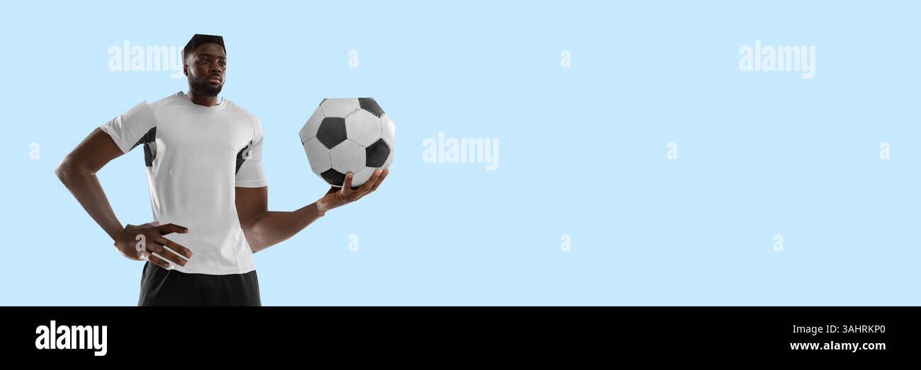 Confident man, soccer player standing with ball ball on blue background ...