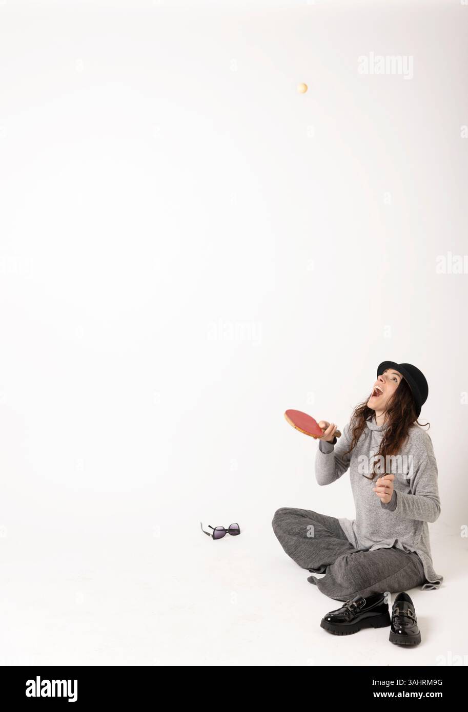 Woman sitting with crossed legs plays ping pong. She has thrown the ...