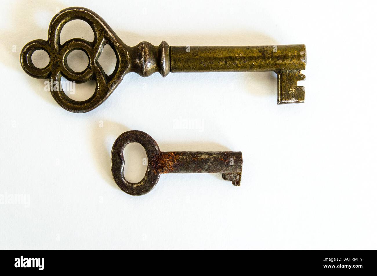 Large and Small Antique Brass Skeleton Keys on White Background, shown ...