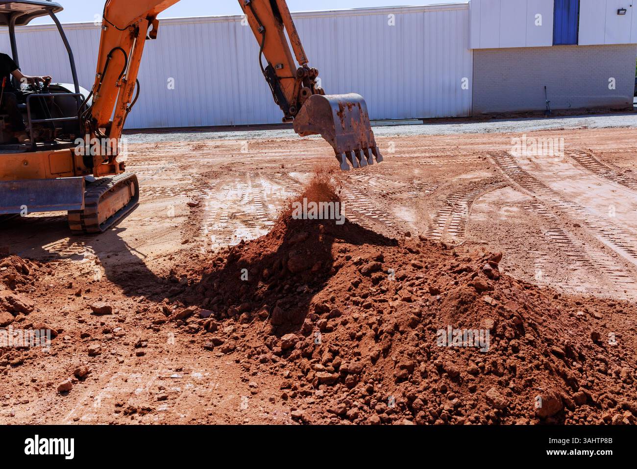 Excavator digs into ground, moving soil during construction activity at ...