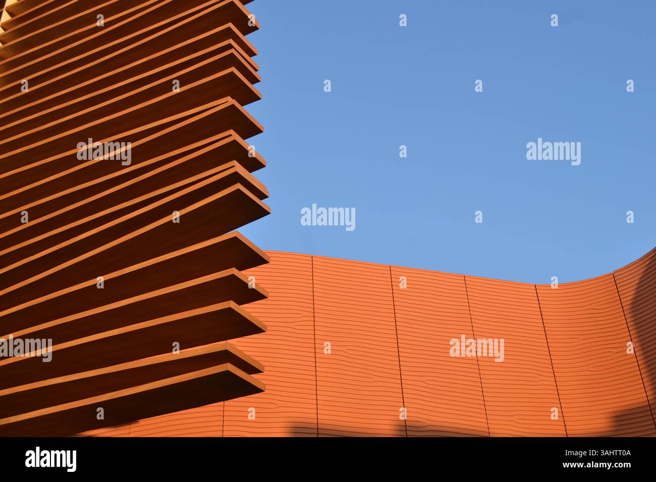 Heap of brown boards, red brick wall and blue sky. Abstract ...