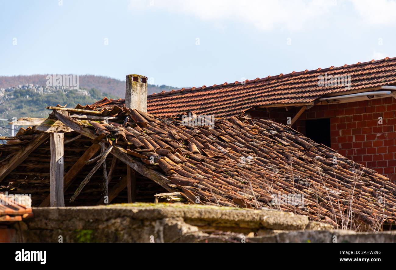 Detail from a neglected roof with old terracotta shingle bricks falling ...