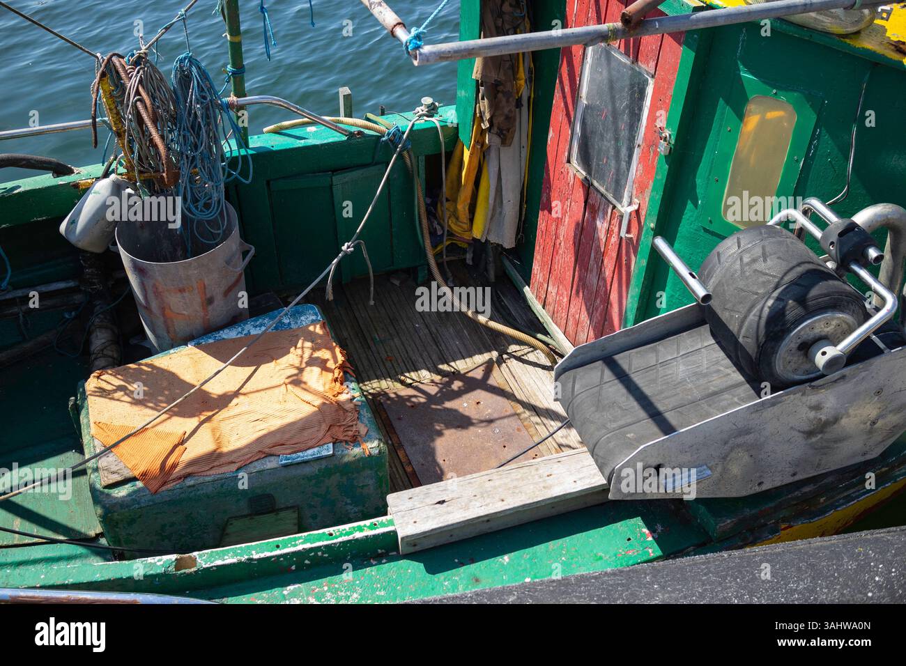 A boat with a green and red interior. The boat has a bucket and a chair ...