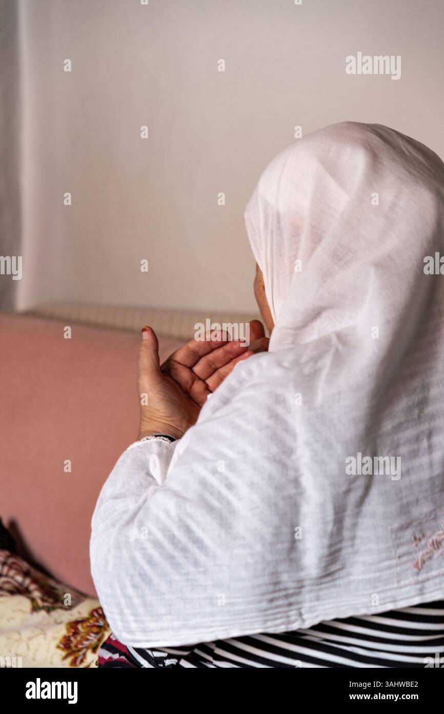 Senior muslim lady reciting the salat in sitting position due to her ...