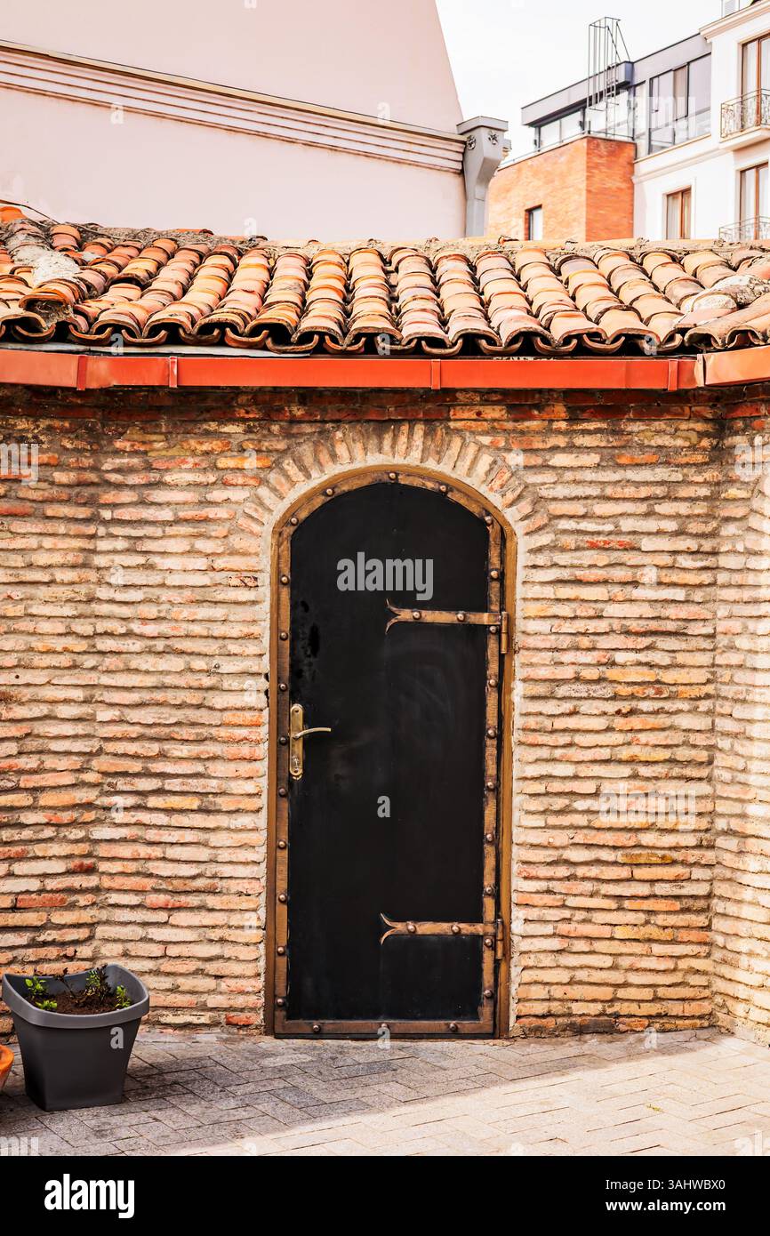 Black metal door with rustic bolts in an arched brick wall under ...