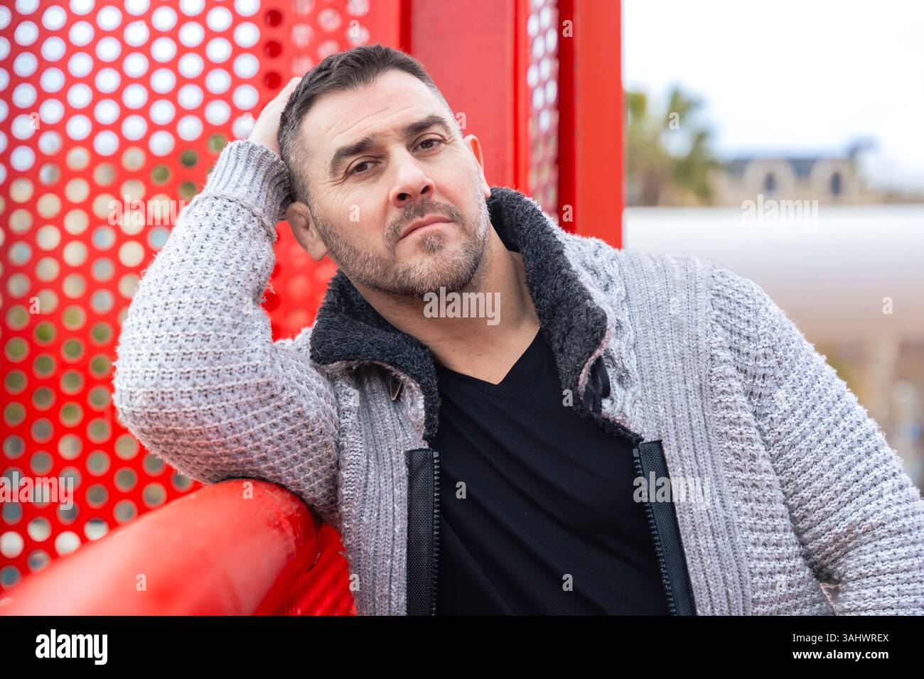Caucasian man looking serious while standing near red structure in ...