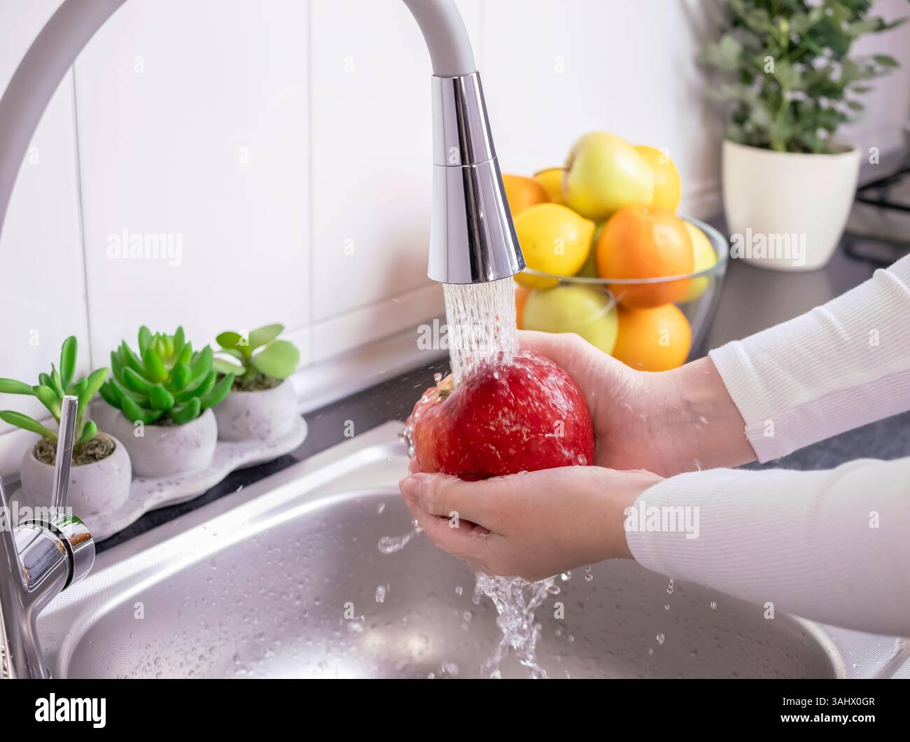 Woman hands washing fresh red apple in the kitchen. Eating healthy raw ...