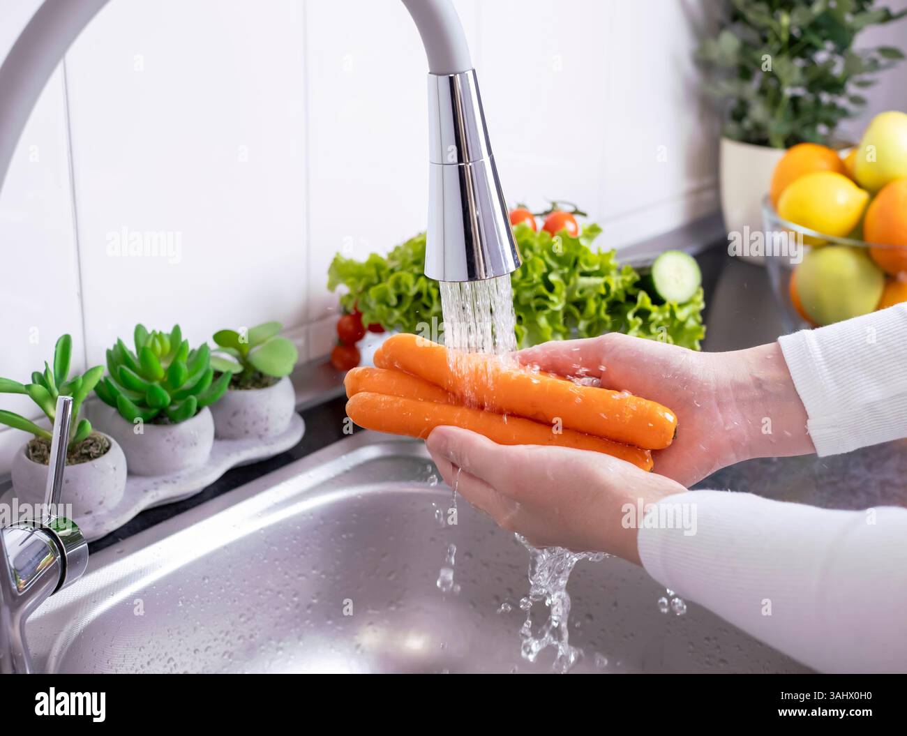 Woman hands washing fresh carrots in the kitchen. Eating healthy raw ...