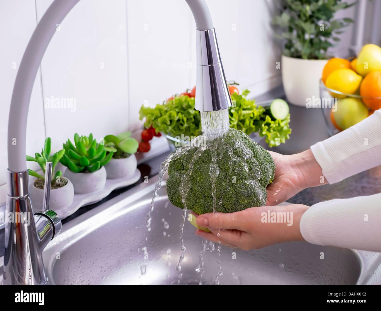 Woman hands washing fresh broccoli in the kitchen. Eating healthy raw ...