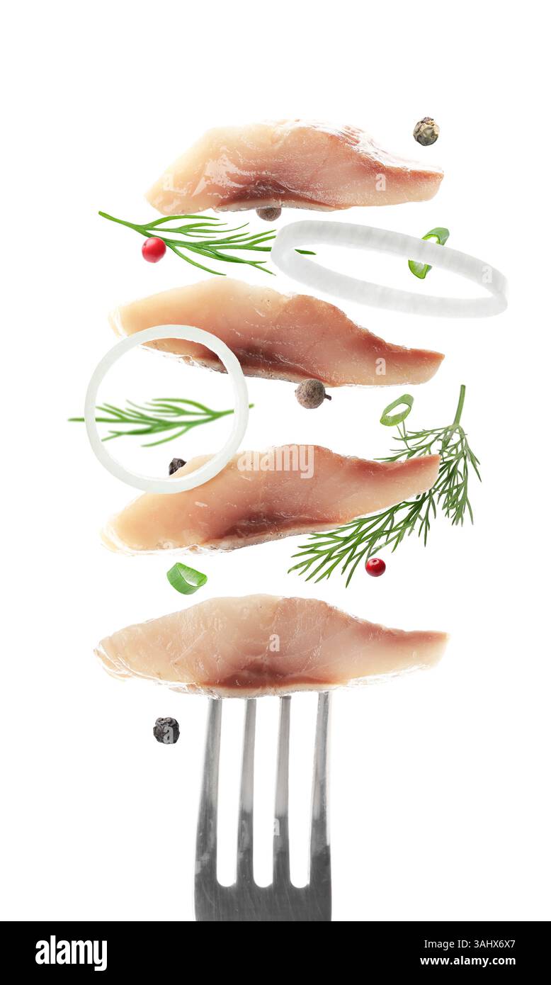 Pieces of herring, onion, dill and peppers mix falling onto fork on ...