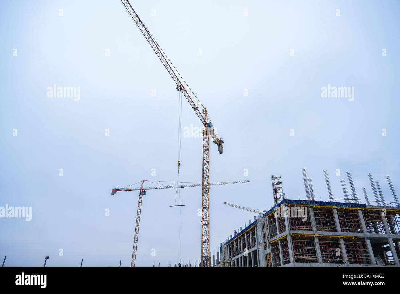 A crane is lifting a large object in front of a building. The sky is ...