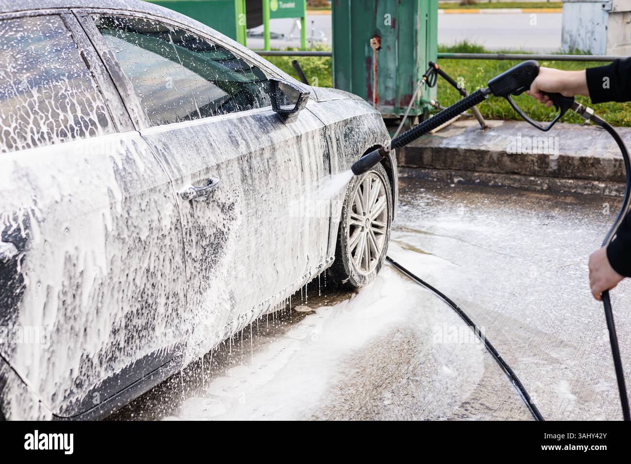 A car coated in thick soap foam is parked at a local service station ...