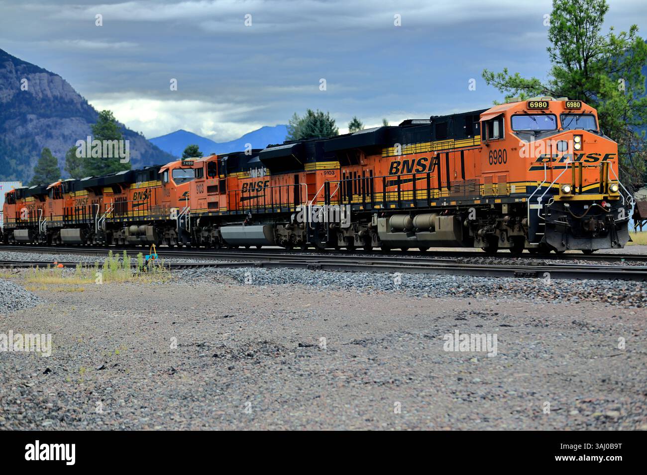 A line of BNSF Railway locomotives, led by engine 6980 in bright orange ...