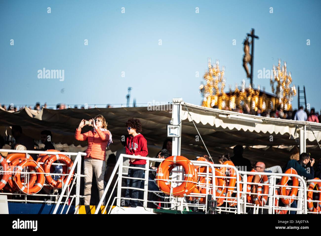 Seville, Spain, March 25 2016, Tourists take photos from a boat while Cristo del Cachorro passes ...
