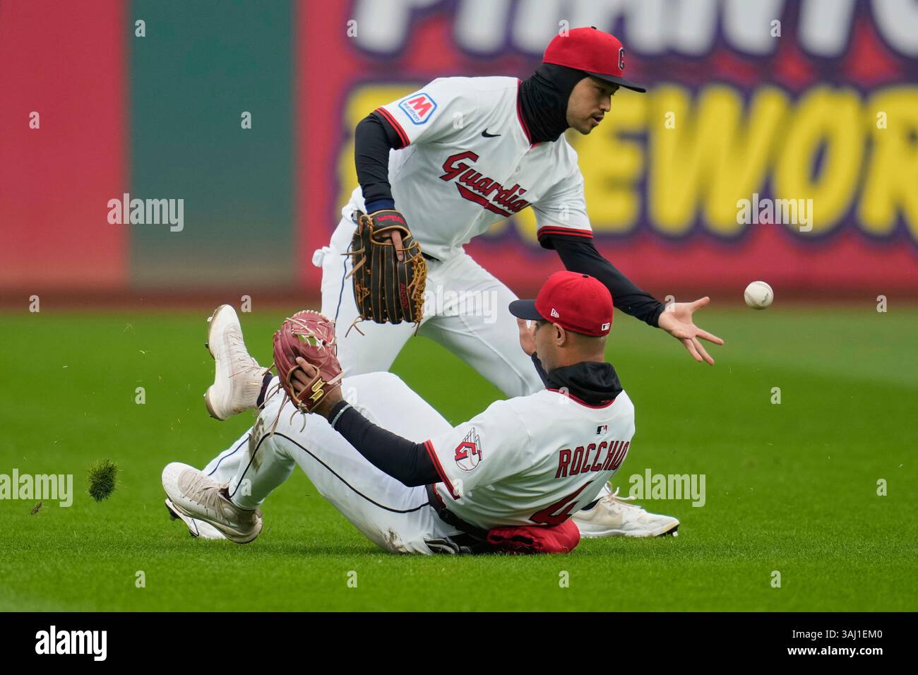 Cleveland Guardians left fielder Steven Kwan, rear, fields a ball hit ...