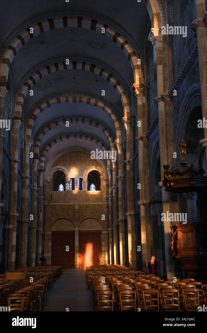 floodlit church's nave with columns, arches and chairs for prayers ...